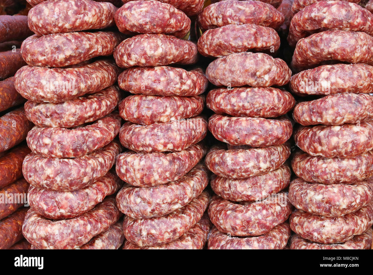 Rings of smoked pork sausage lie on the counter of a street vendor ...