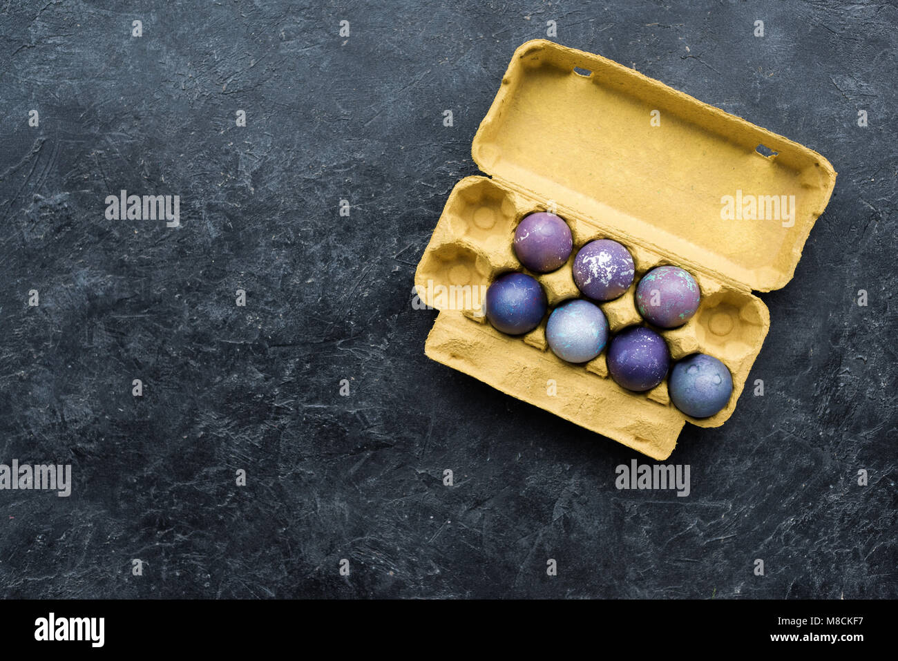 Purple colored eggs in carton on dark background Stock Photo - Alamy