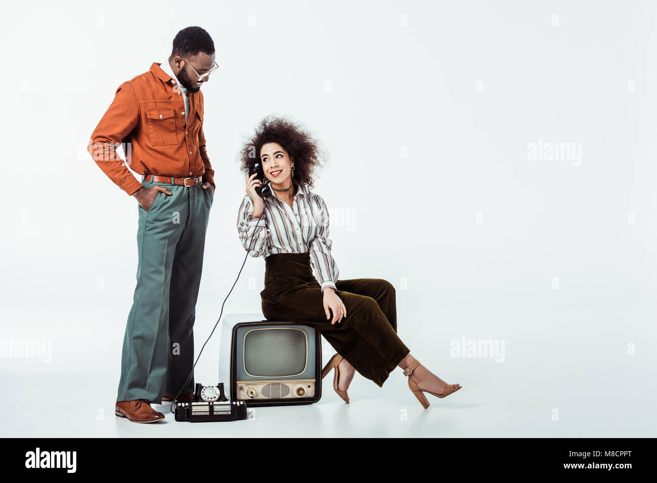 african american retro styled girlfriend sitting on vintage television ...