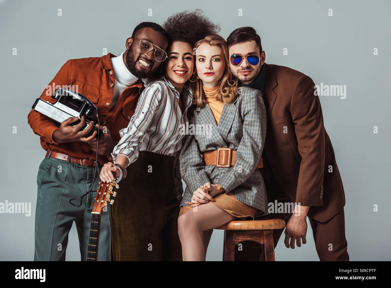 multicultural retro styled friends with guitar and telephone looking at ...