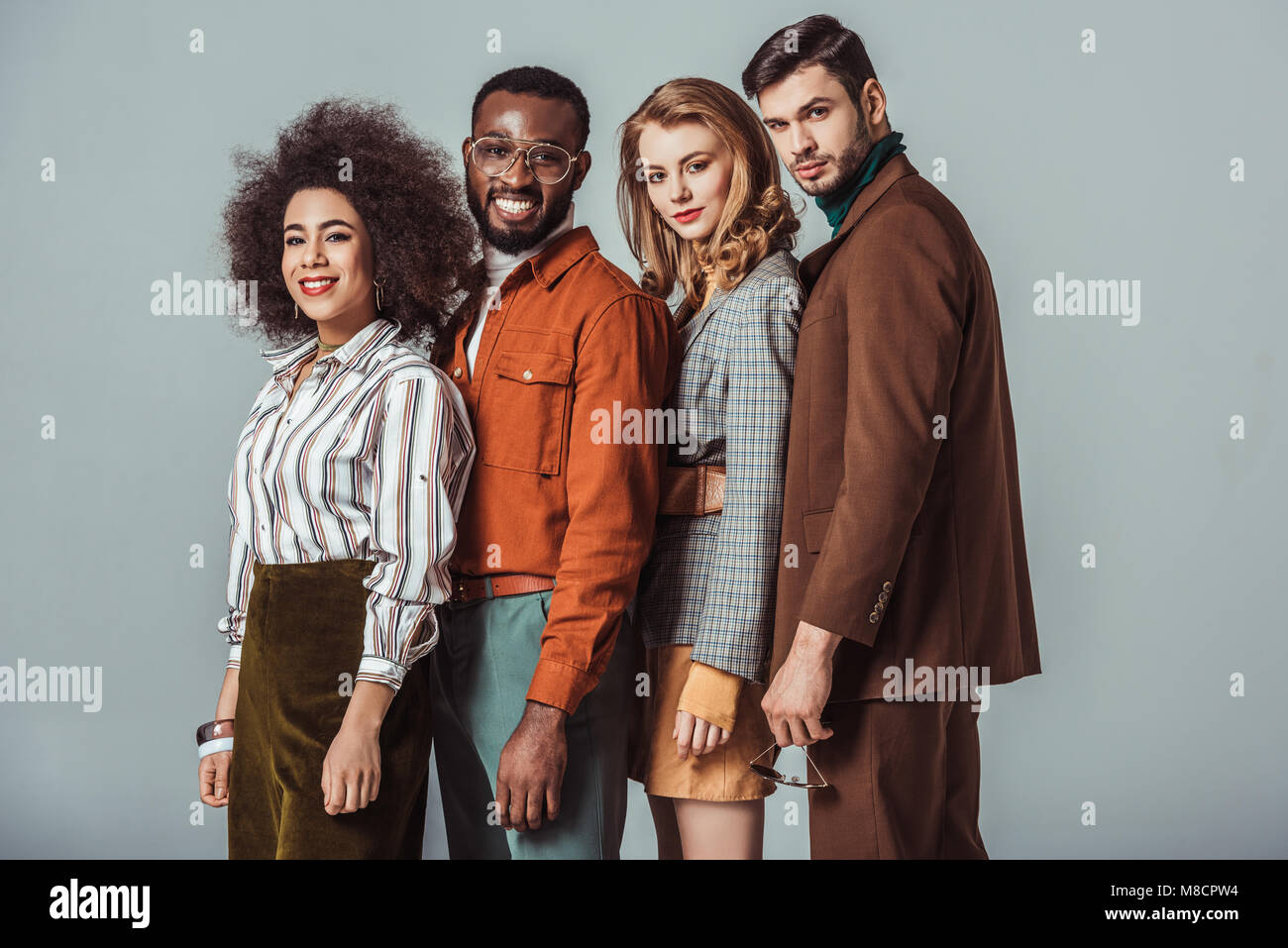 smiling multicultural retro styled friends standing isolated on grey ...