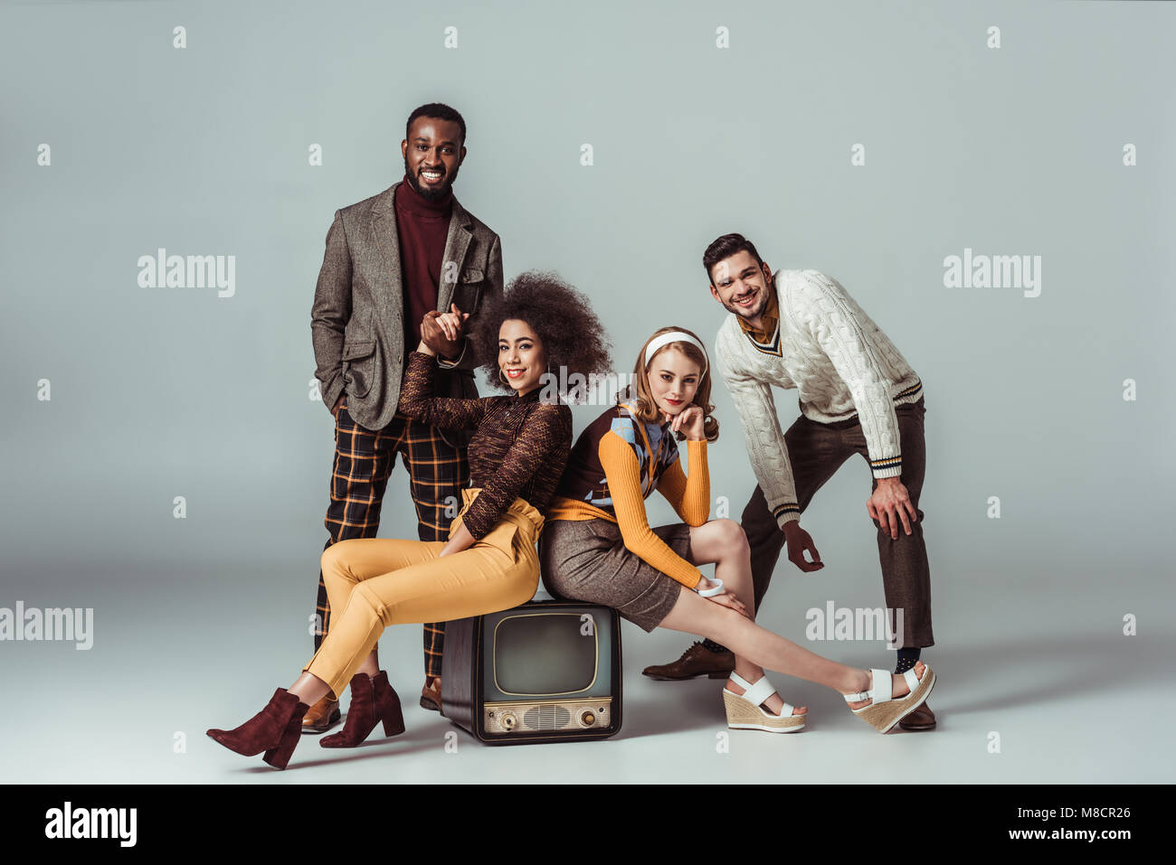 multicultural retro styled friends posing with vintage television on ...