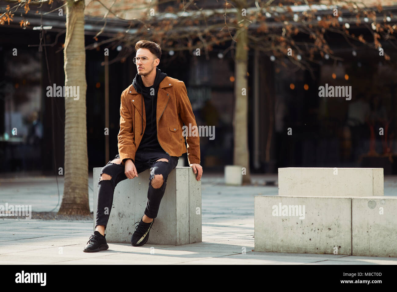 Model looking man sit on the bench in modern park background, look on ...