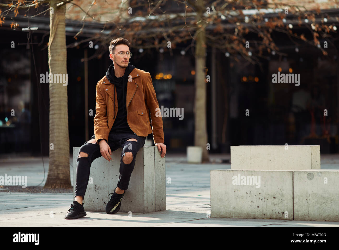 Model looking man sit on the bench in modern park background, look on ...