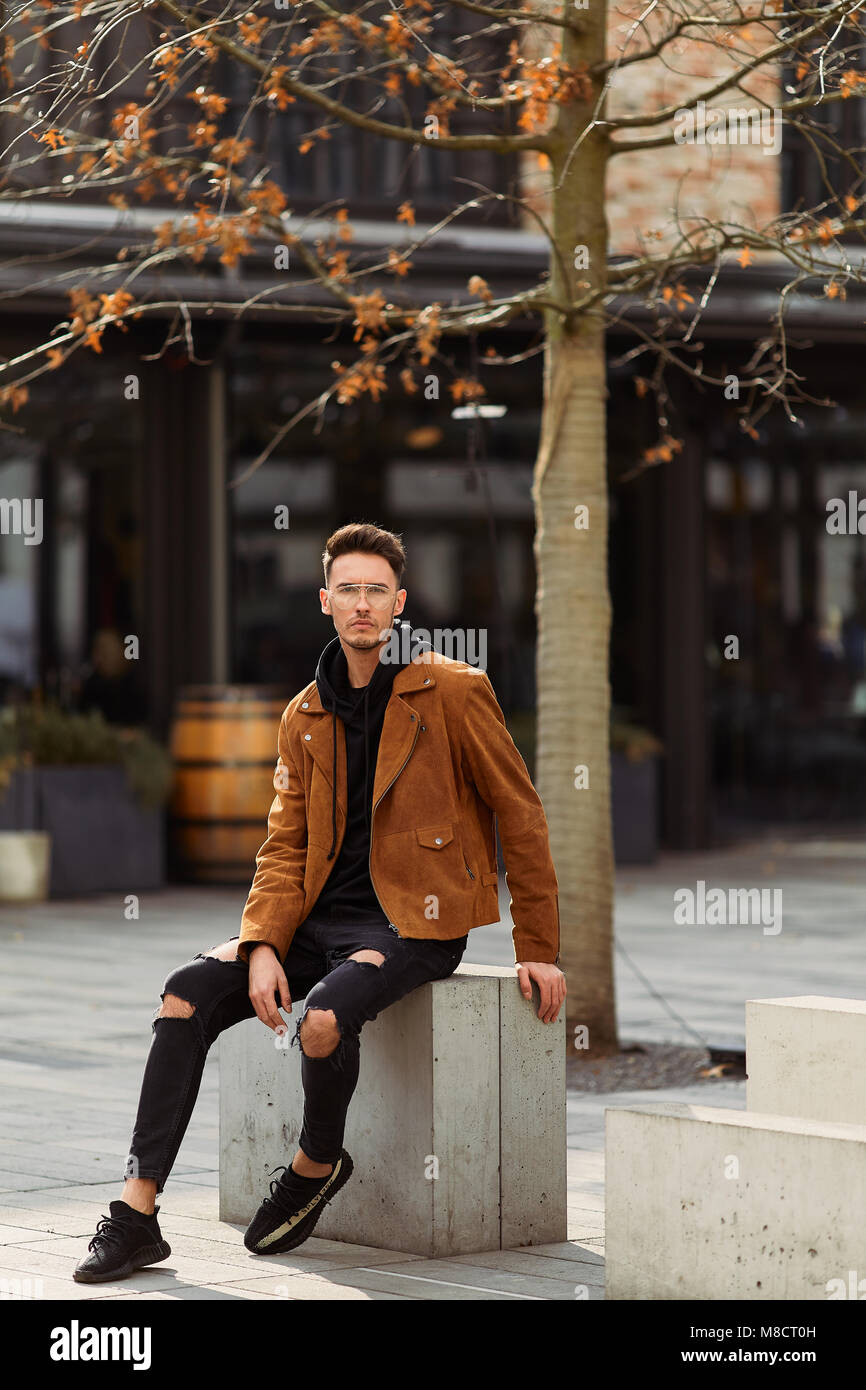 Model looking man sit on the bench in modern park background, look on ...