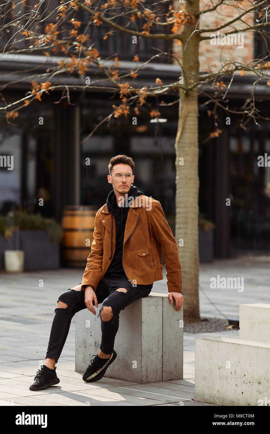 Model looking man sit on the bench in modern park background, look on ...
