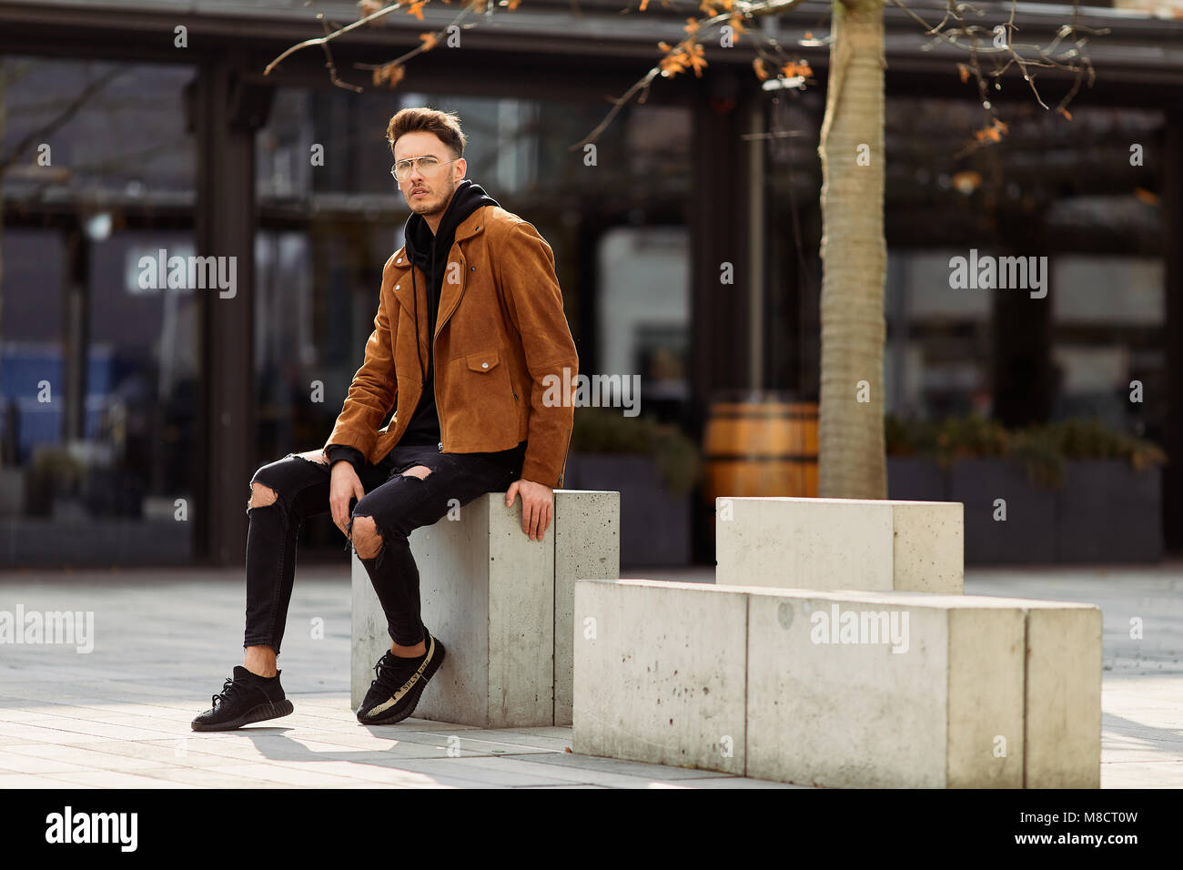 Model looking man sit on the bench in modern park background, look on ...