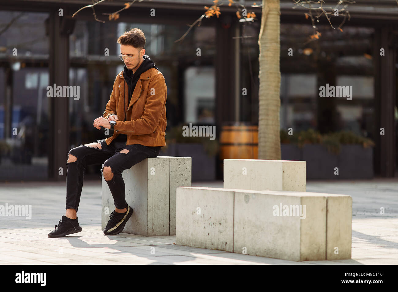 Model looking man sit on the bench in modern park background, look on ...