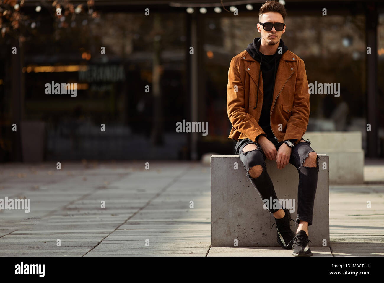 Model looking man sit on the bench in modern park background, look on ...