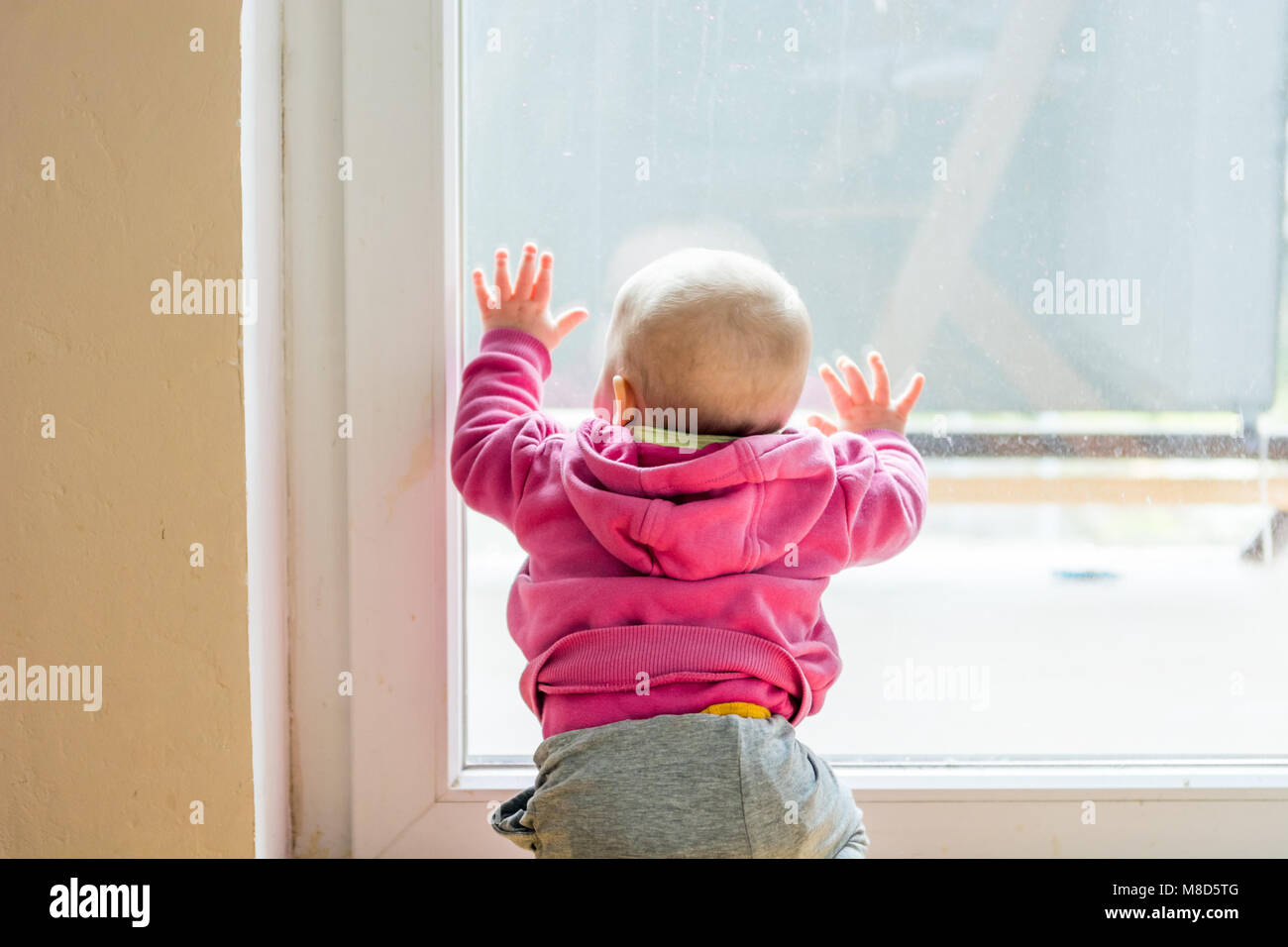 Baby girl looking through balcony Stock Photo - Alamy