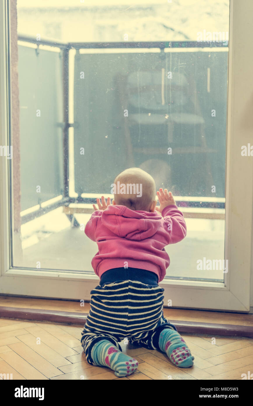 Baby girl looking through balcony Stock Photo - Alamy