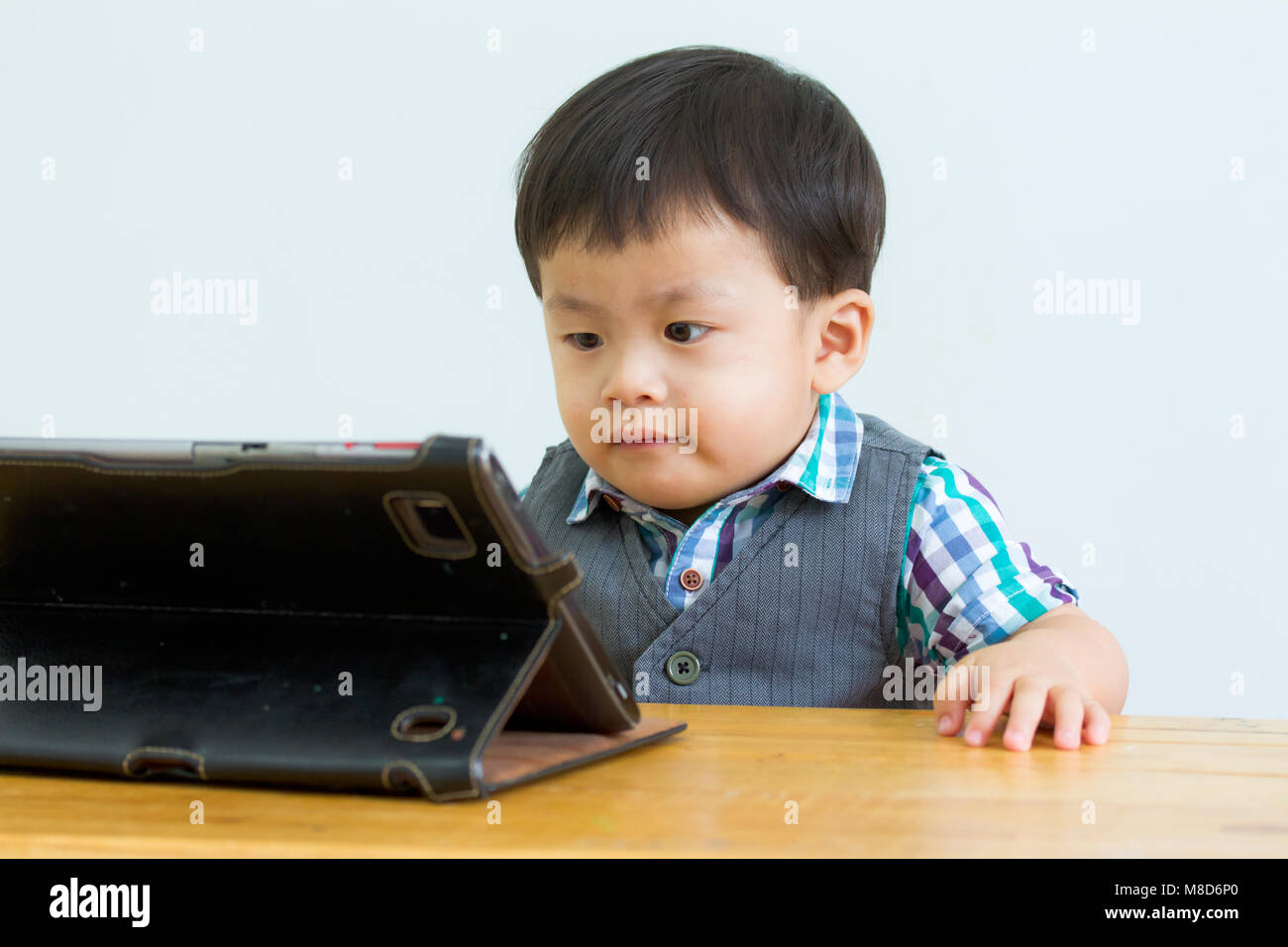 Asian cute a little boy looking tablet on the table Stock Photo - Alamy