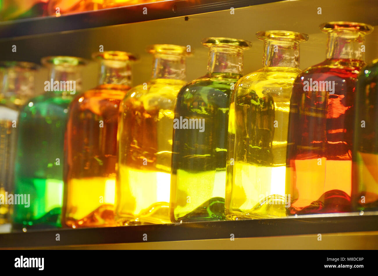 Multi-colored bottles in the window.Electric lighting creates a ...