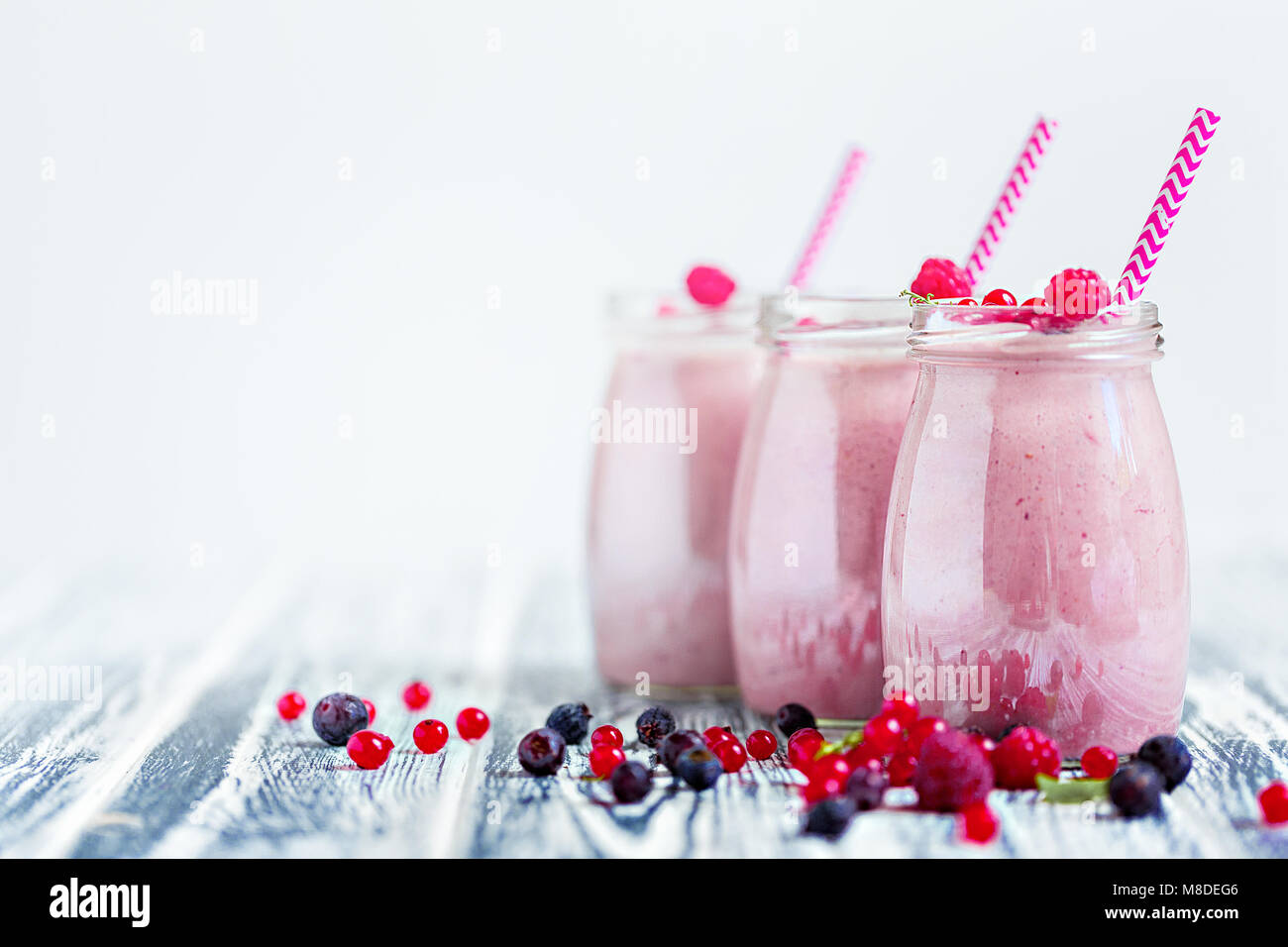 Row of milkshake jars with berries aside Stock Photo - Alamy