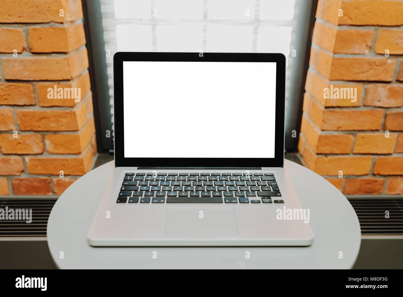 Laptop with blank screen on table - brick wall background Stock Photo ...