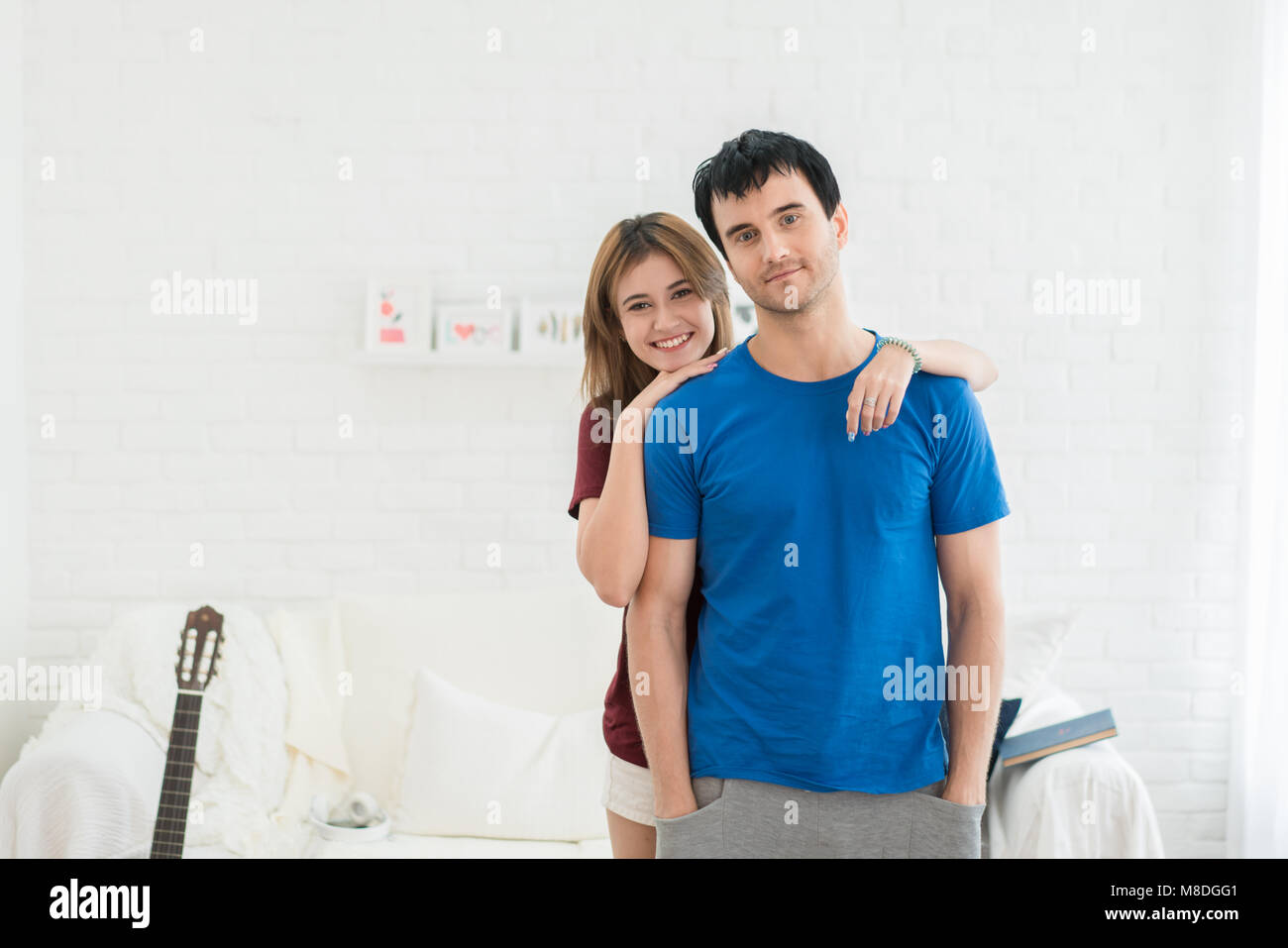 Beautiful young couple is hugging, looking at camera and smiling while ...