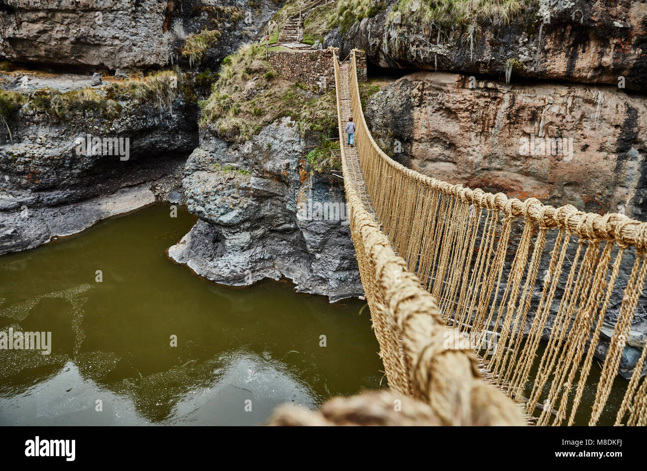 Rear view of boy crossing Inca rope bridge, Huinchiri, Cusco, Peru ...
