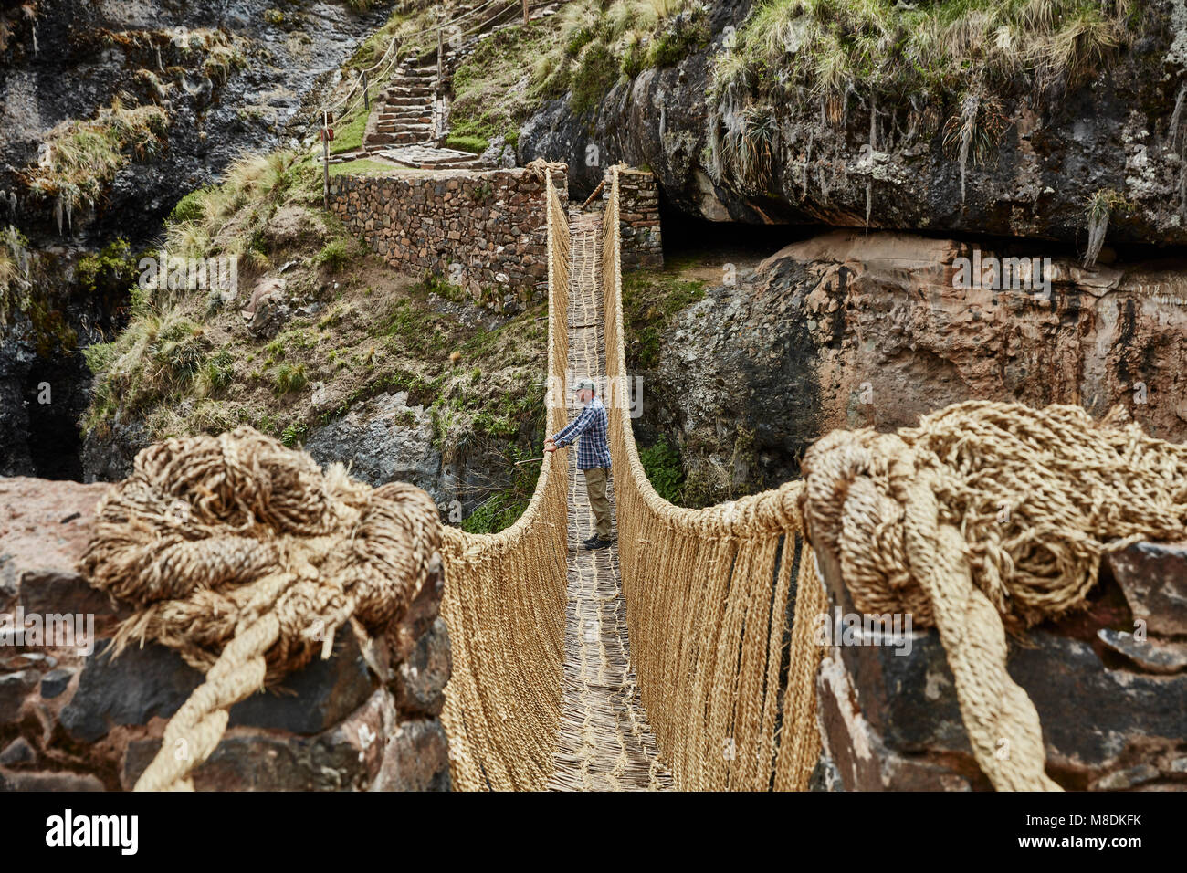 Male tourist looking out from Inca rope bridge, Huinchiri, Cusco, Peru ...