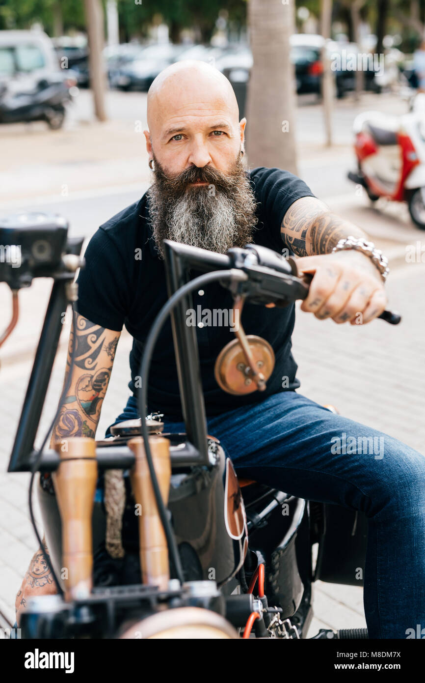 Portrait of mature male hipster astride motorcycle in parking lot Stock ...