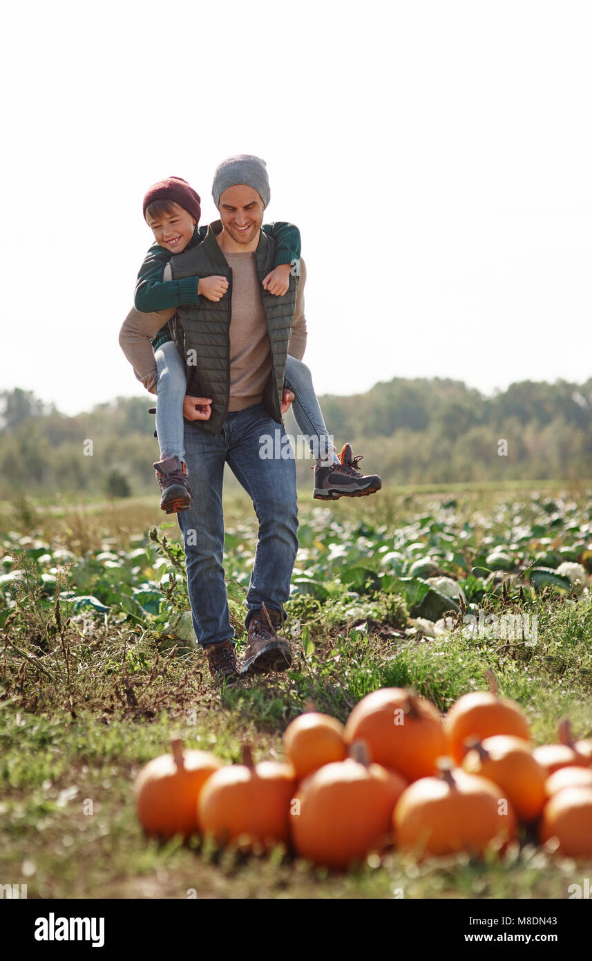 Man giving son piggyback ride in field at pumpkin patch Stock Photo - Alamy