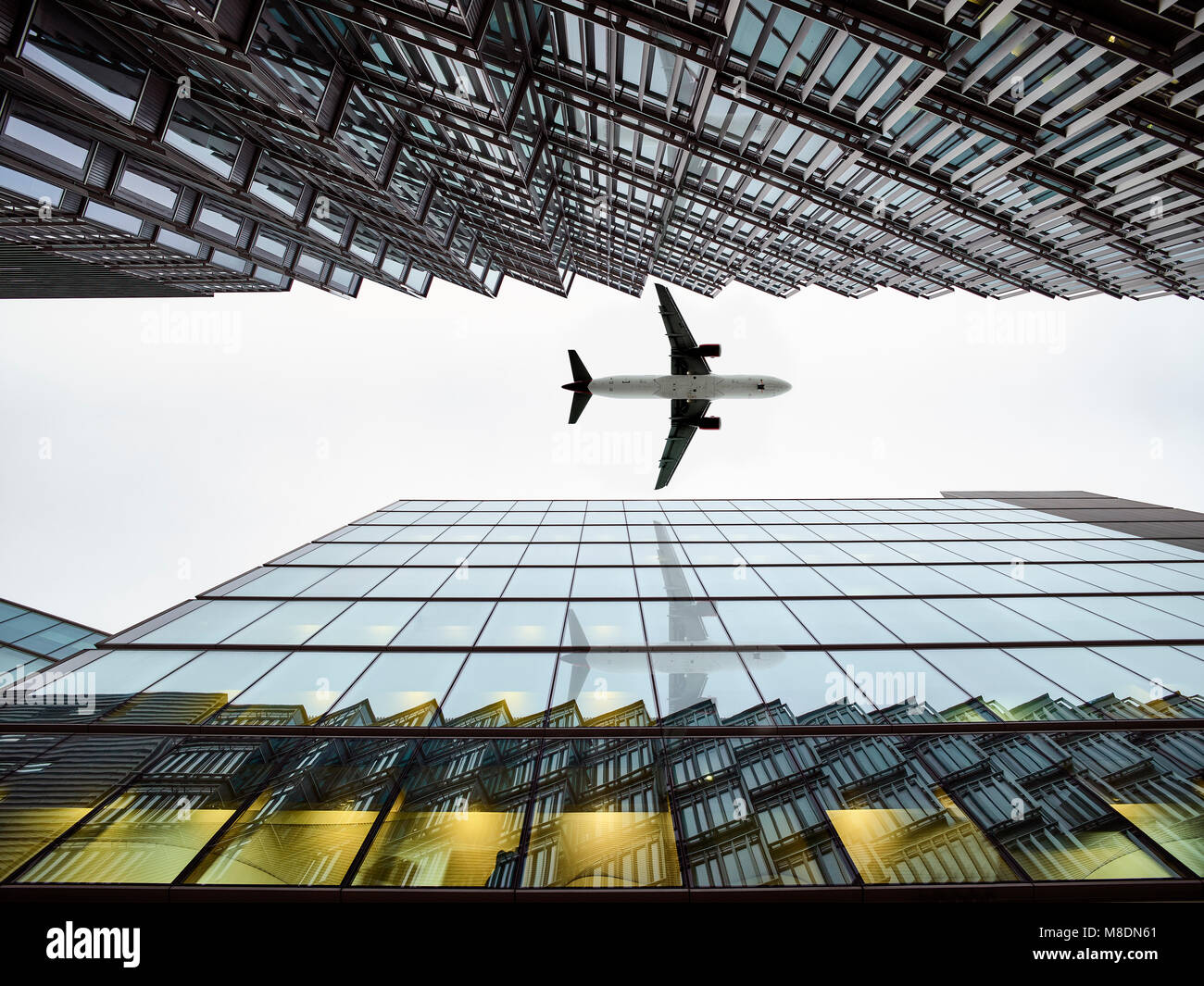 Low angle view of airplane flying between modern buildings, London City ...