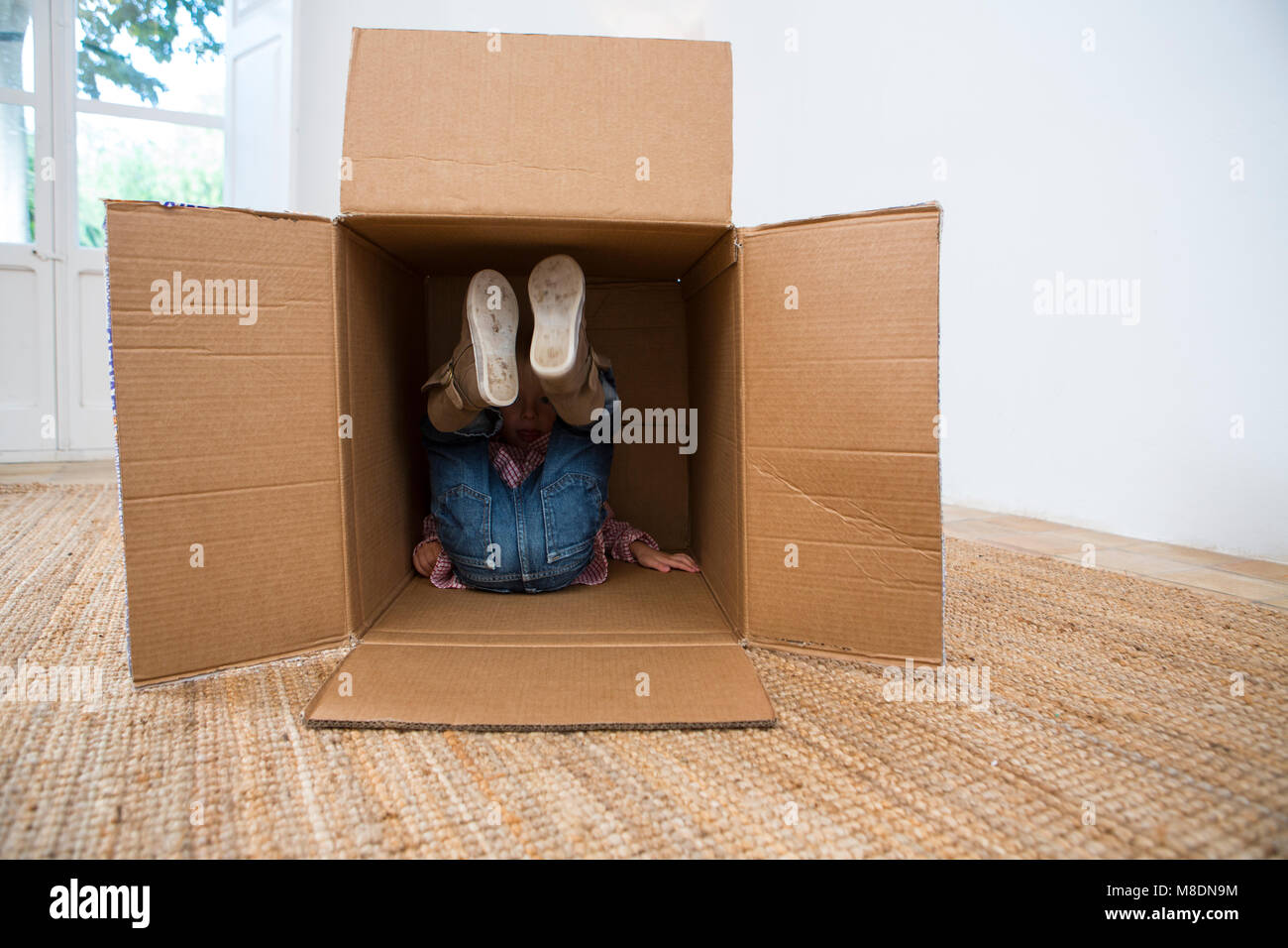 Boy lying in cardboard box with legs raised Stock Photo - Alamy