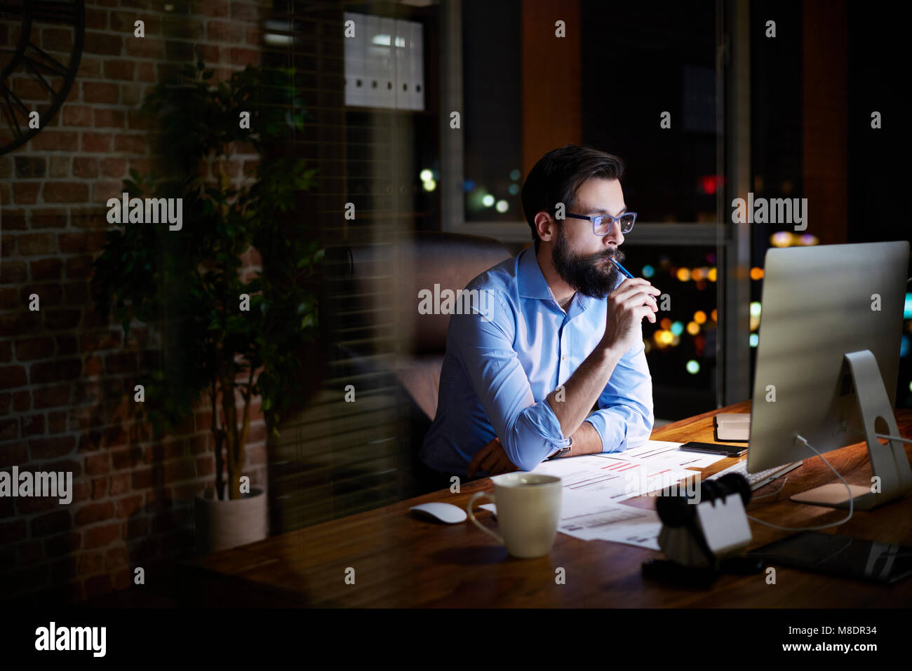 Young businessman looking at computer on office desk at night Stock ...