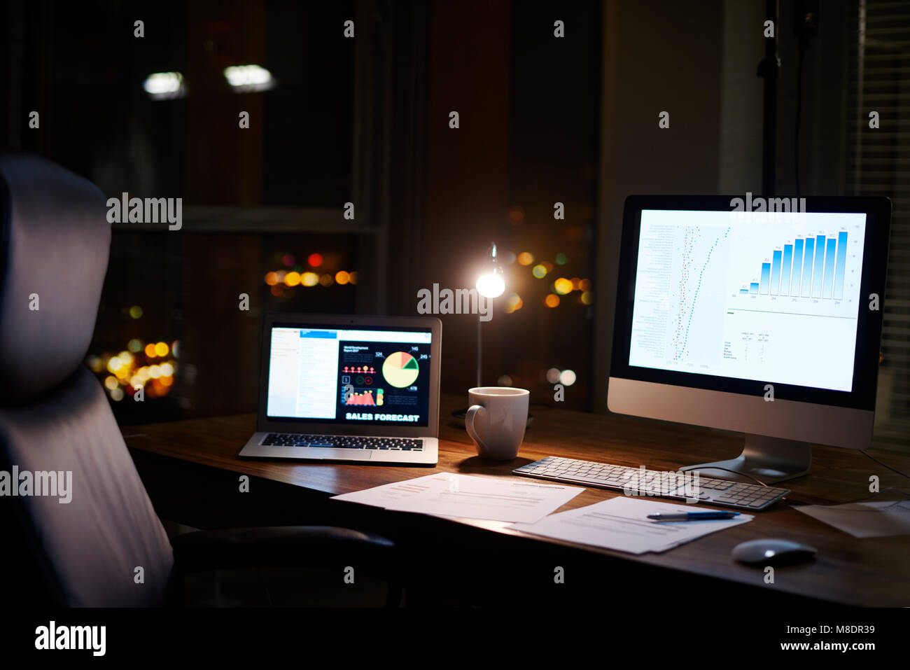 Laptop and computer on office desk at night Stock Photo - Alamy
