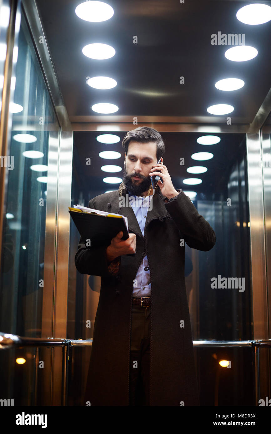Young businessman in elevator making smartphone call Stock Photo - Alamy