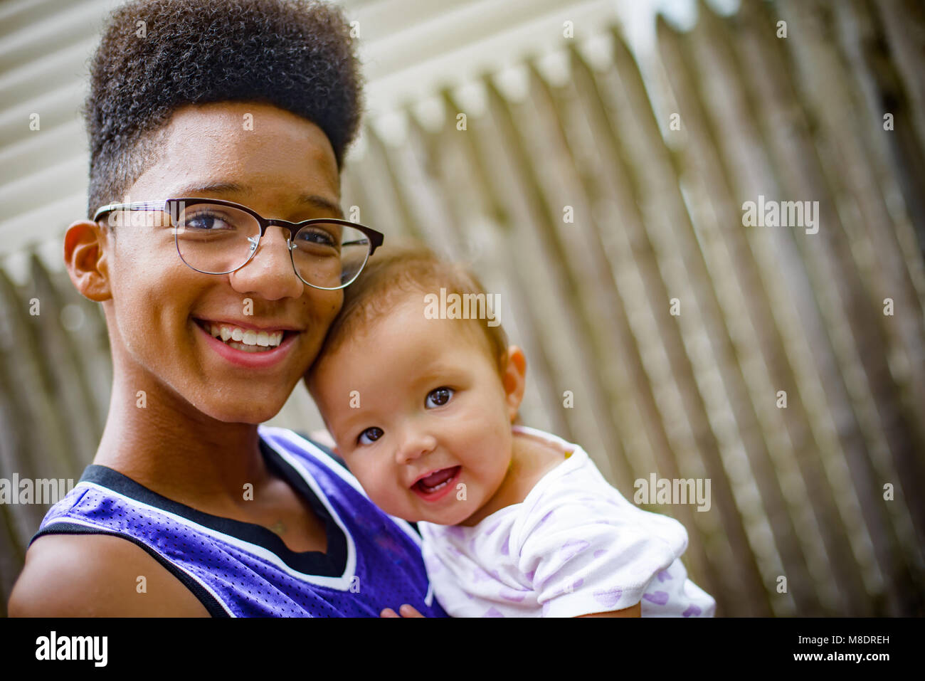 Portrait of teenage boy carrying baby girl in arms Stock Photo - Alamy