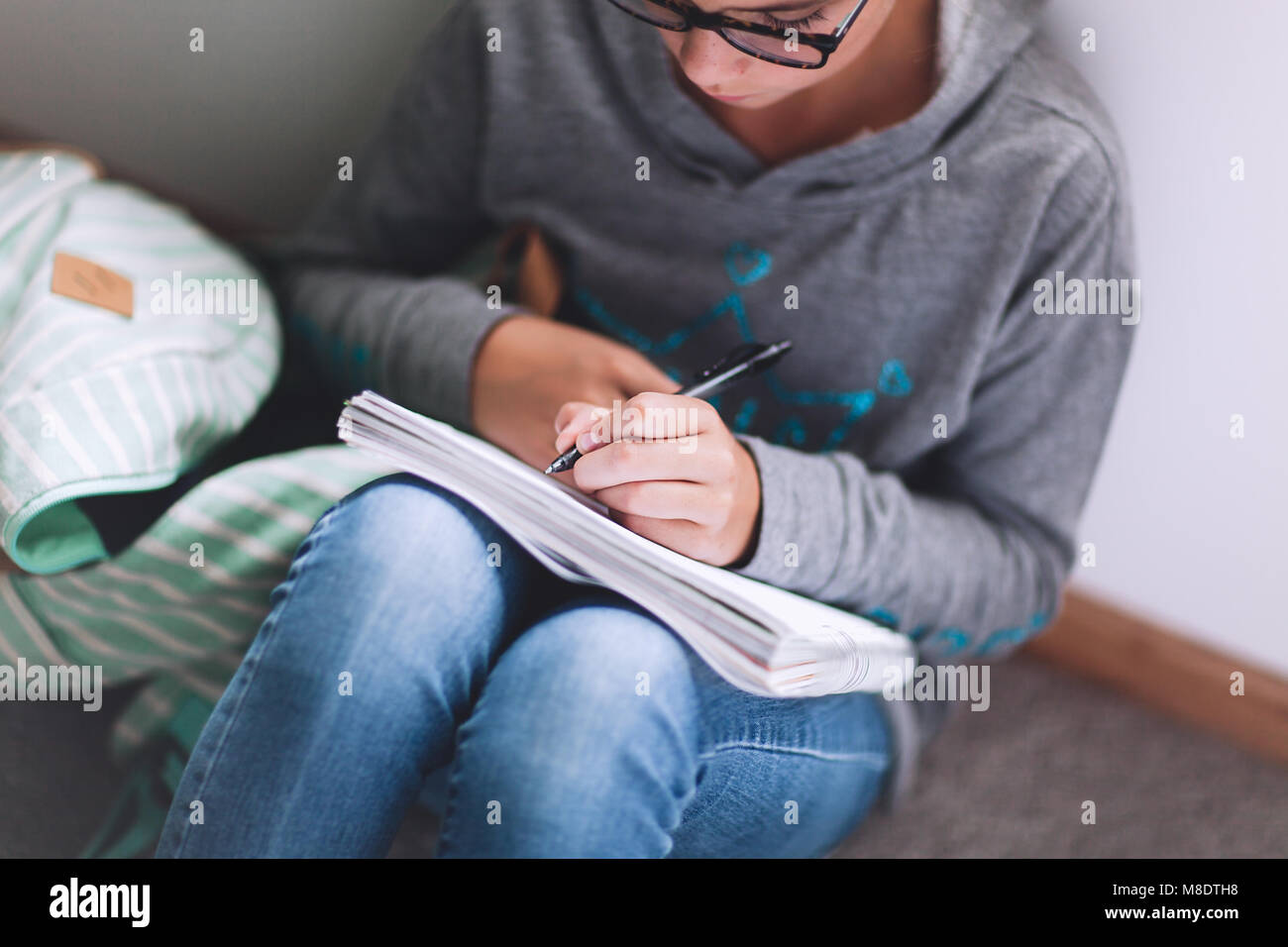 Girl sitting on floor writing up homework Stock Photo - Alamy