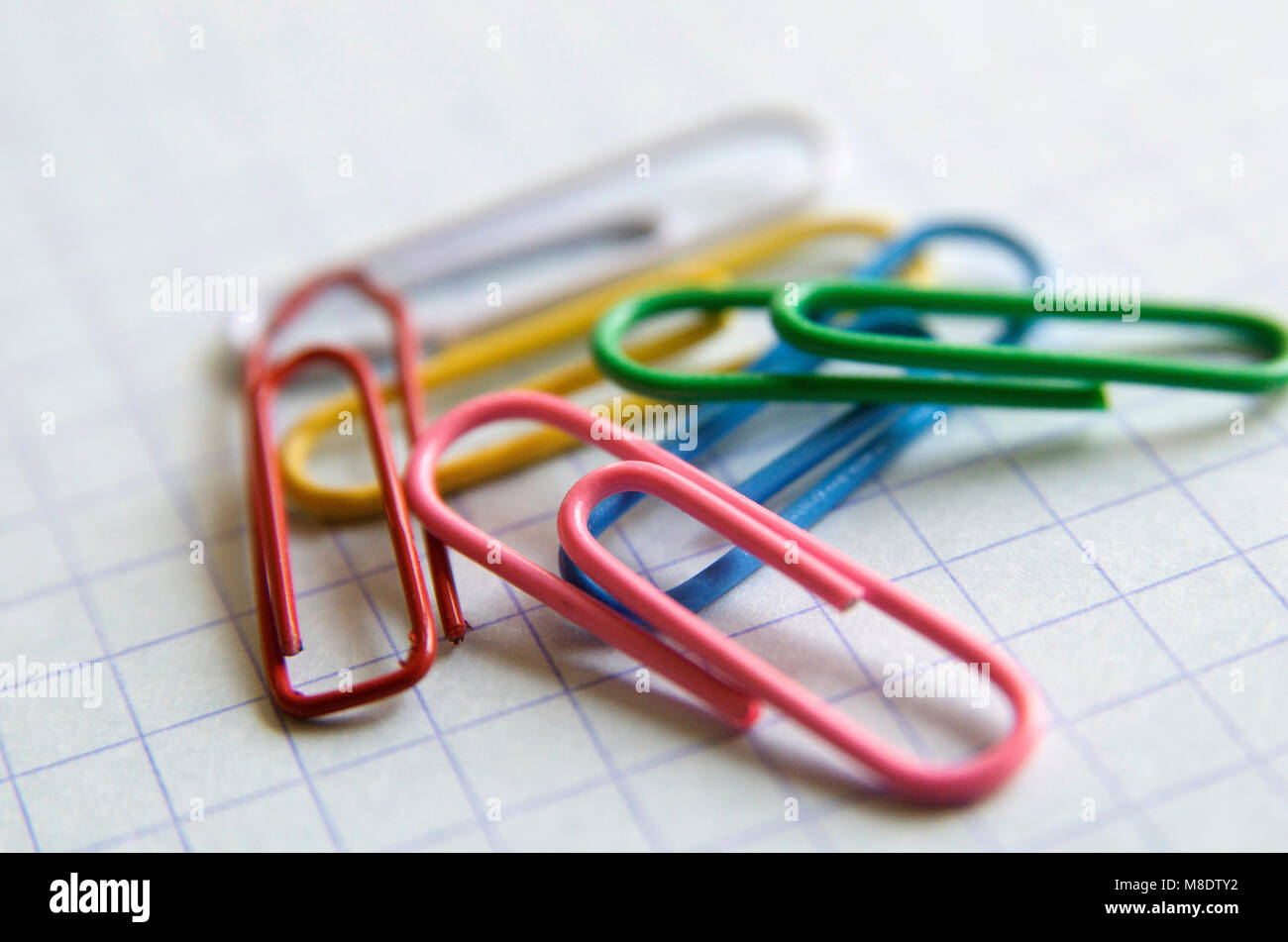 Paper clips on office paper background Stock Photo - Alamy