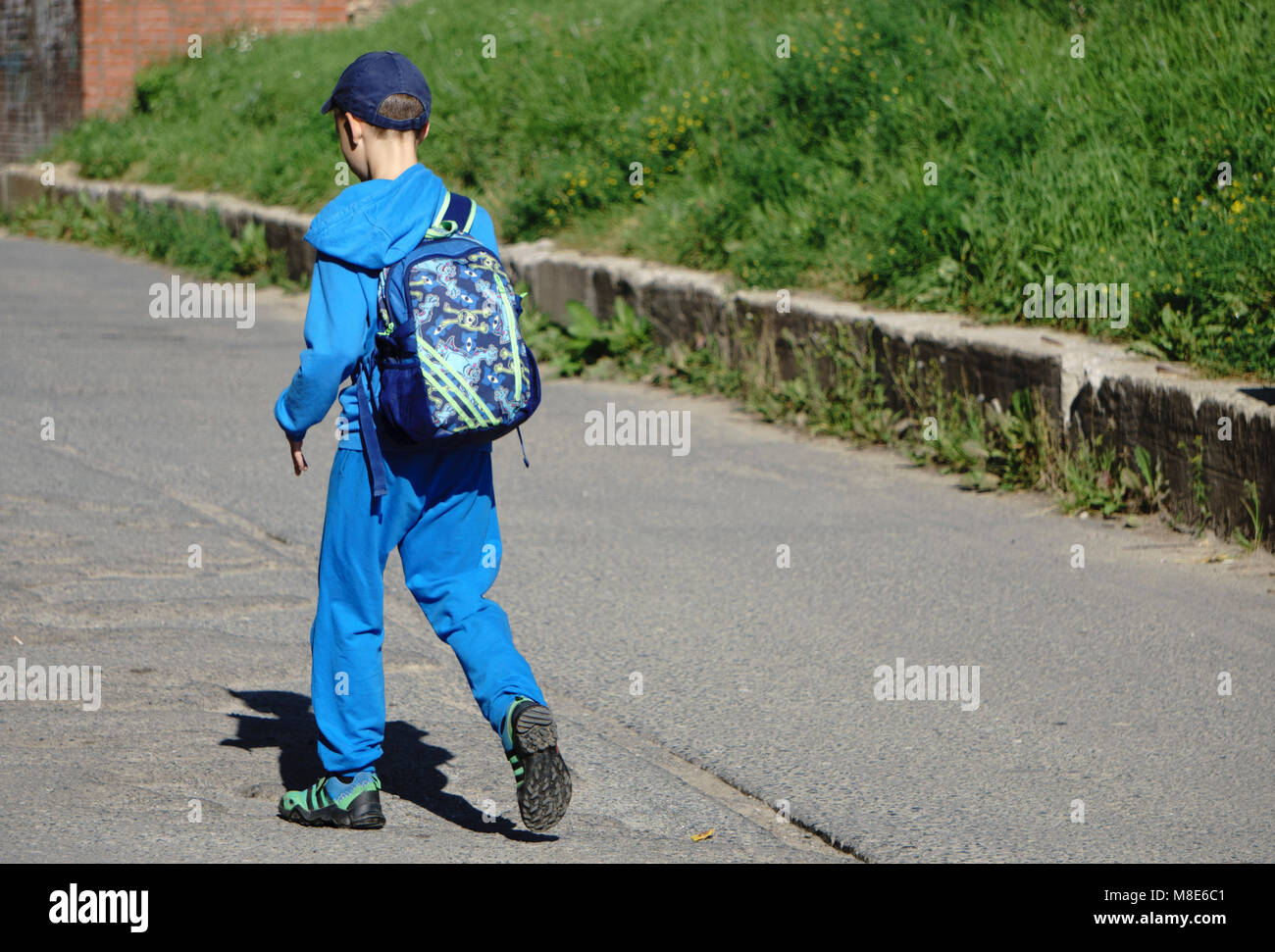 small happy school kid coming from home with bag to school early in the ...