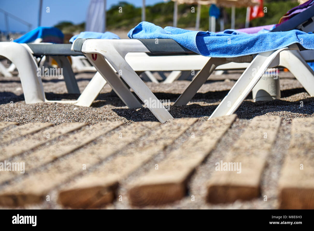 Empty deck chairs with blue towels on beach near sea low angle view ...