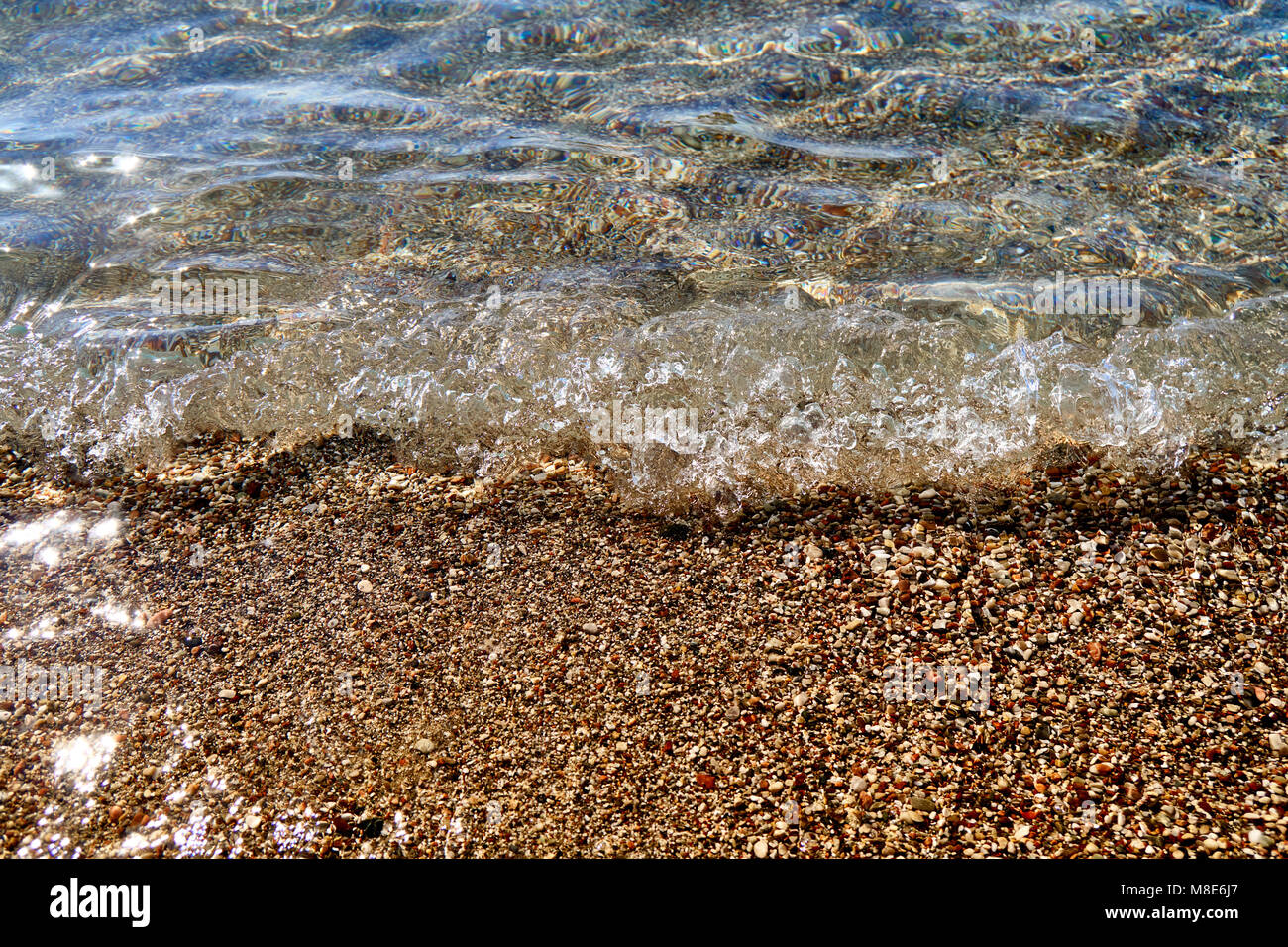 Crystal clean water washes coarse sand lying on beach of sea. Wet ...