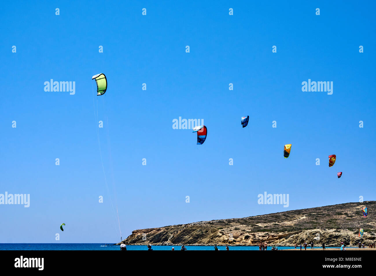 Bright colorful kitesurfer parachutes for surfing fly high across clear ...