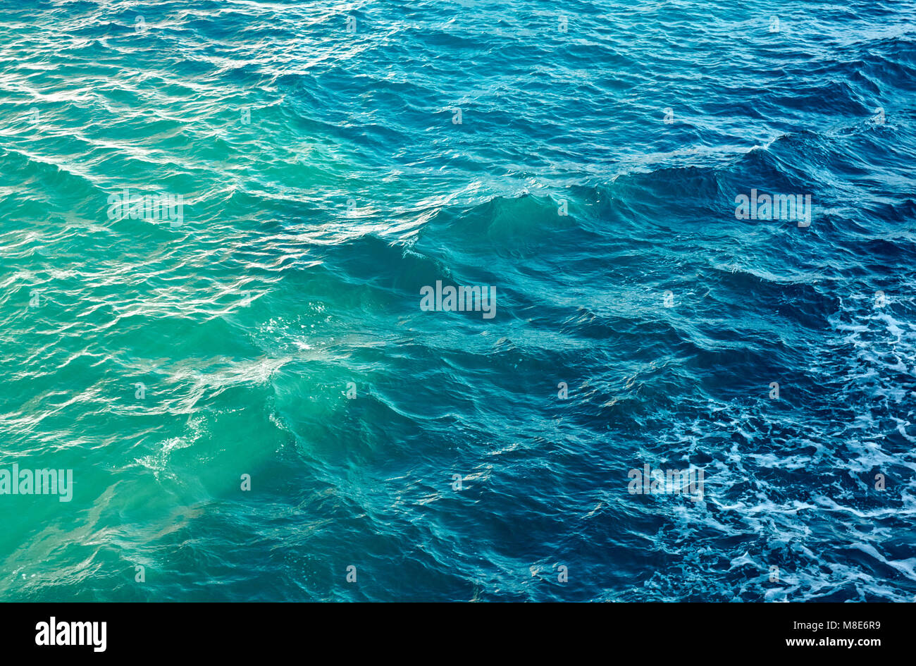 Small waves and ripples on blue sea water reflecting bright sunlight on ...