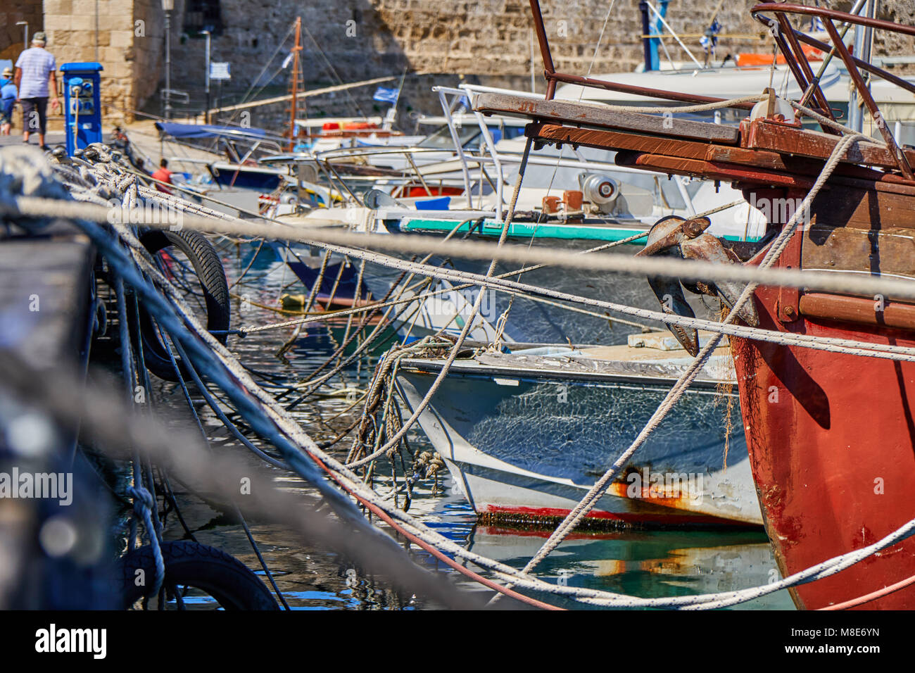 Different boats moored to pier with coloured ropes and shoreside bitts ...