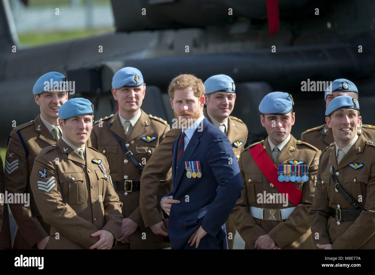 Prince Harry (centre) poses for a photograph in front of an Apache ...