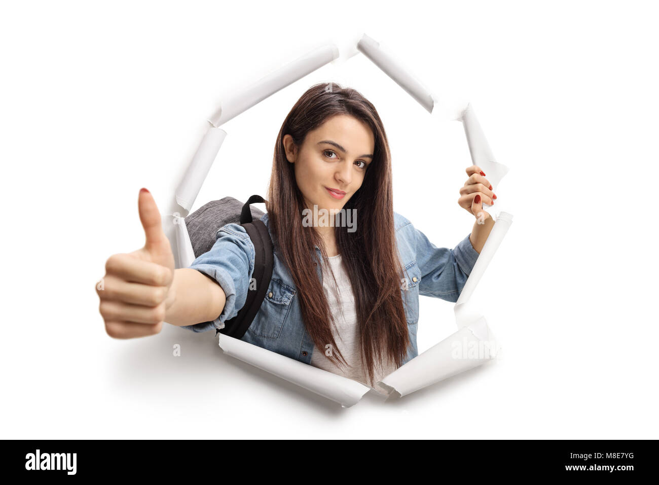Female teenage student breaking through paper and making a thumb up ...