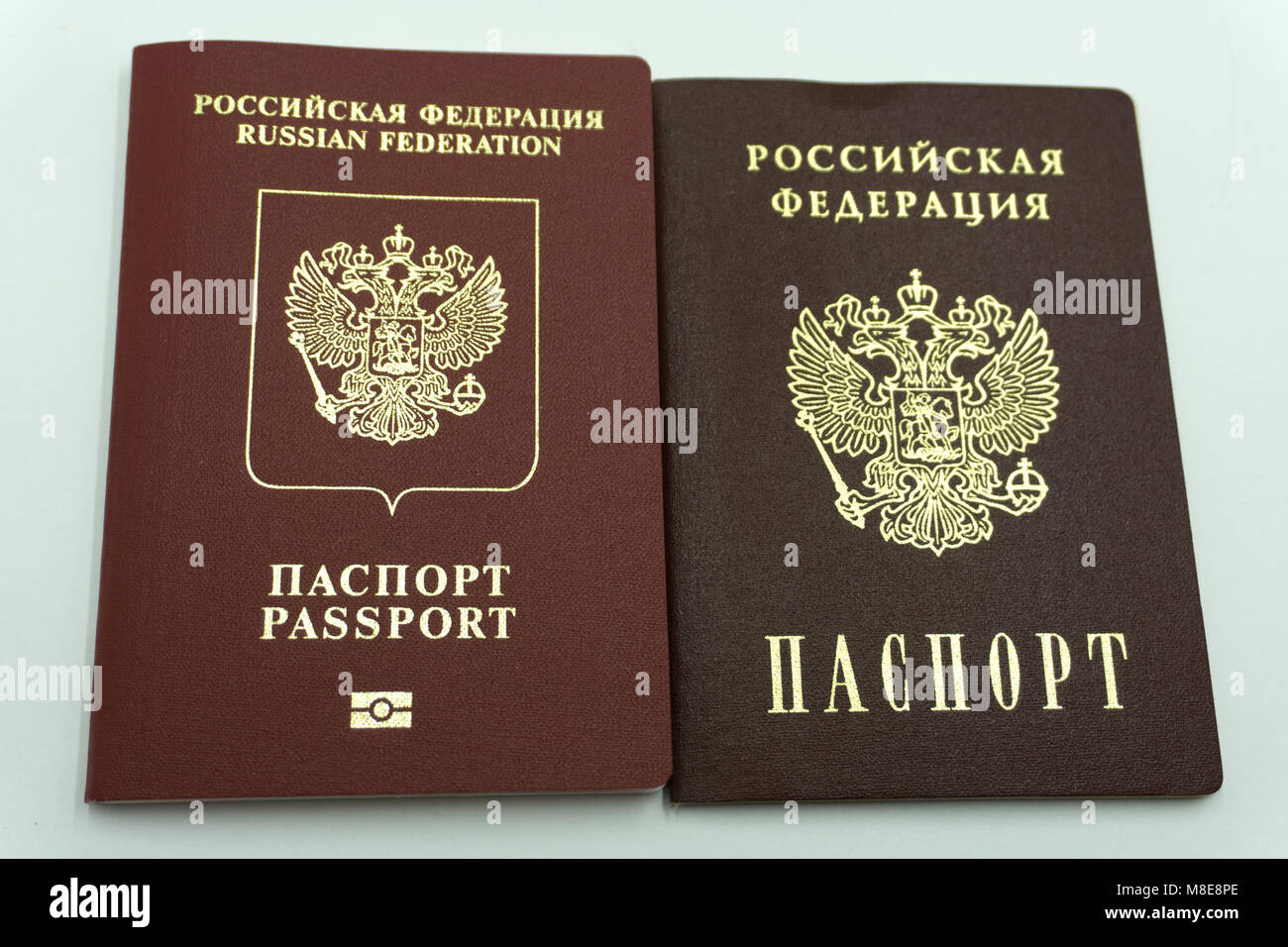 Two dark brown passport located on fine-textured red background ...
