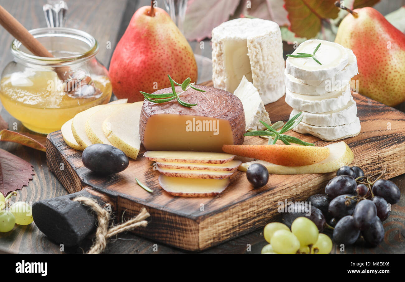 Set of fine cheeses with fruit and honey. Camembert. Bree. Grapes ...
