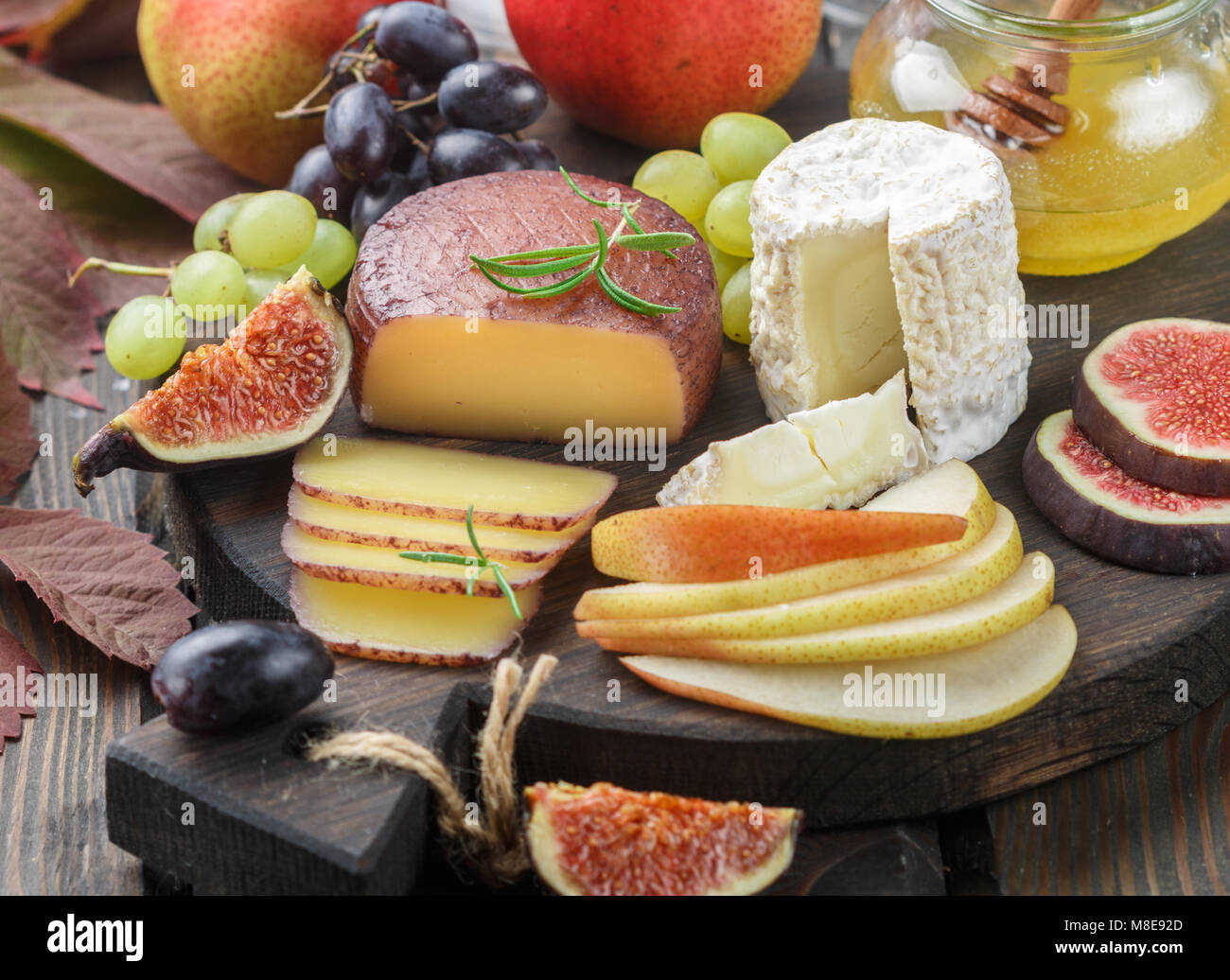 Set of fine cheeses with fruit and honey. Camembert. Bree. Grapes, figs ...