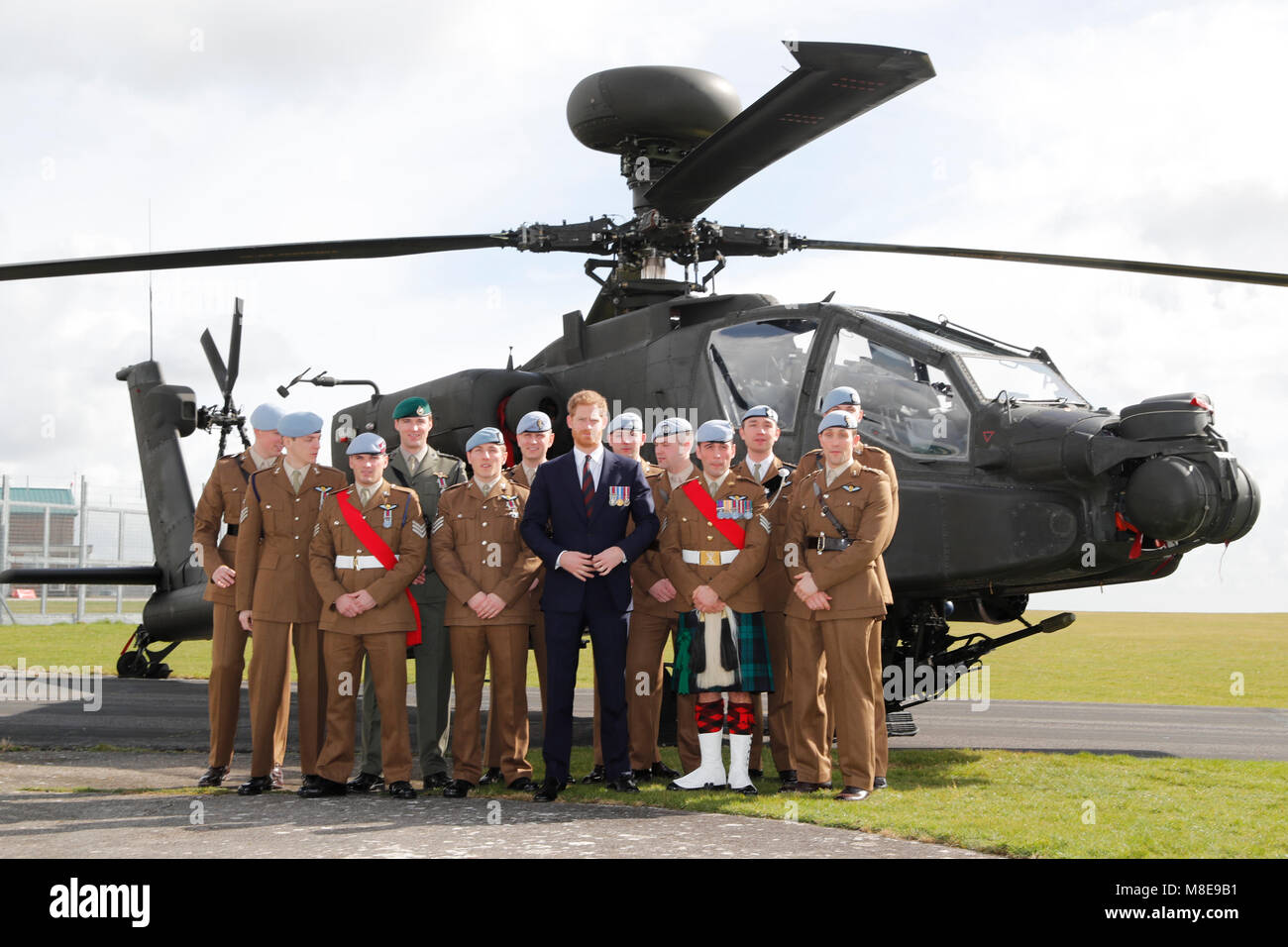Prince Harry (centre) poses for a photograph in front of an Apache ...