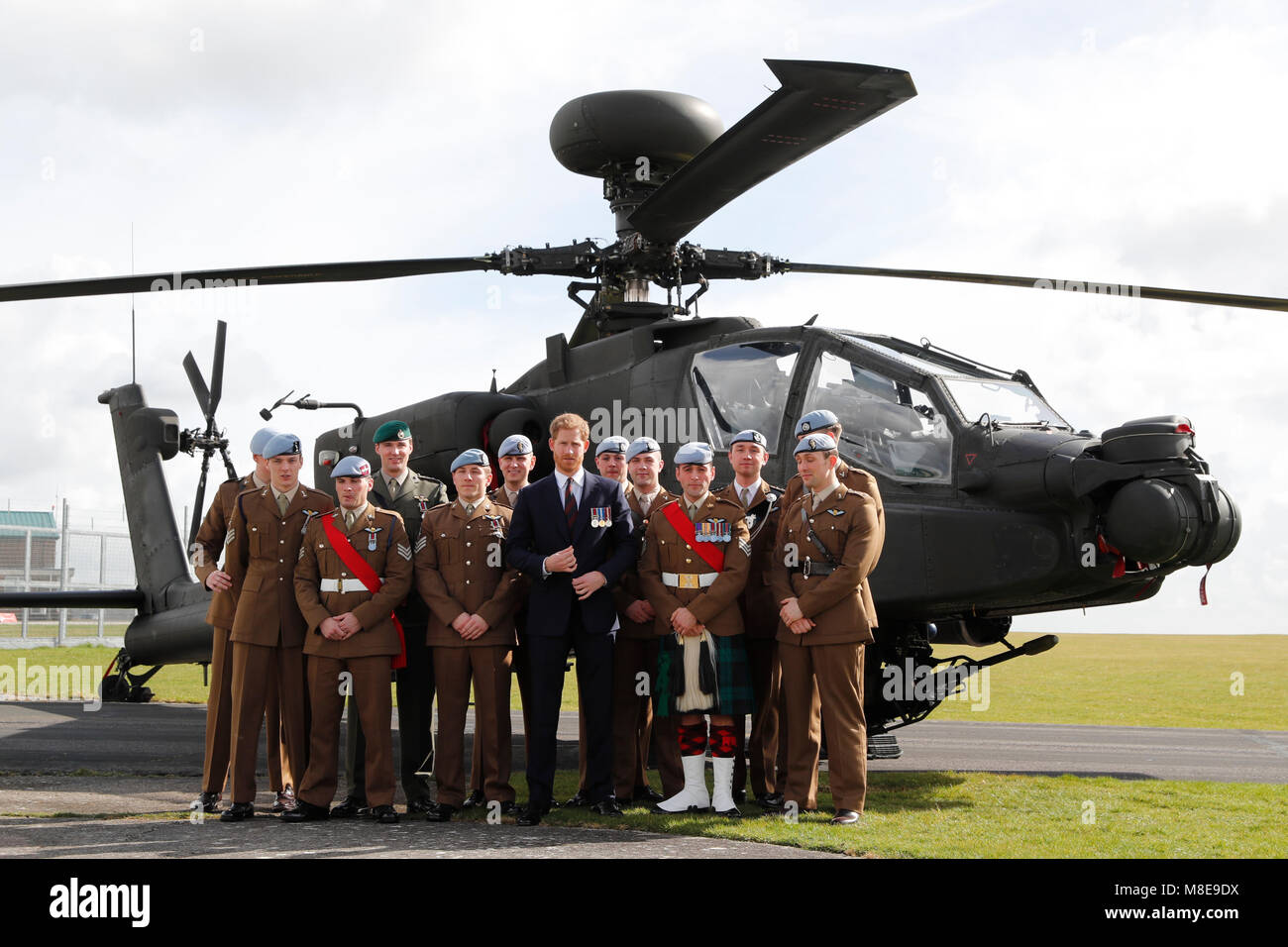 Prince Harry (centre) poses for a photograph in front of an Apache ...