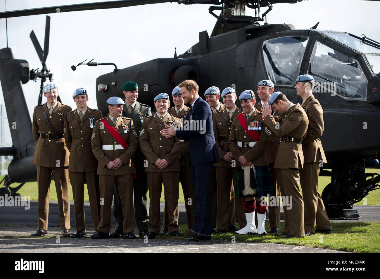 Prince Harry (centre poses for a photograph in front of an Apache ...