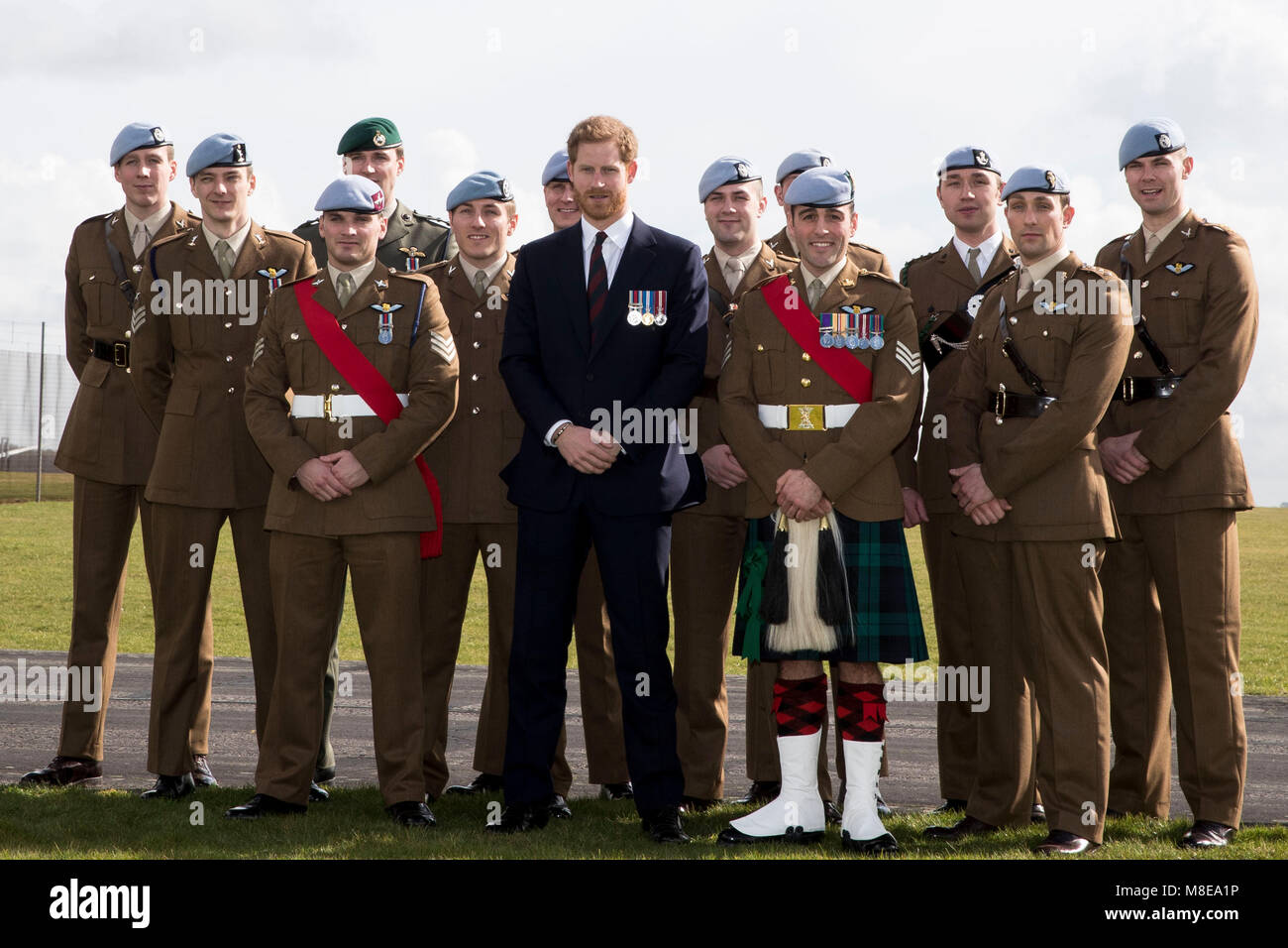Prince Harry (centre) poses for a photograph in front of an Apache ...