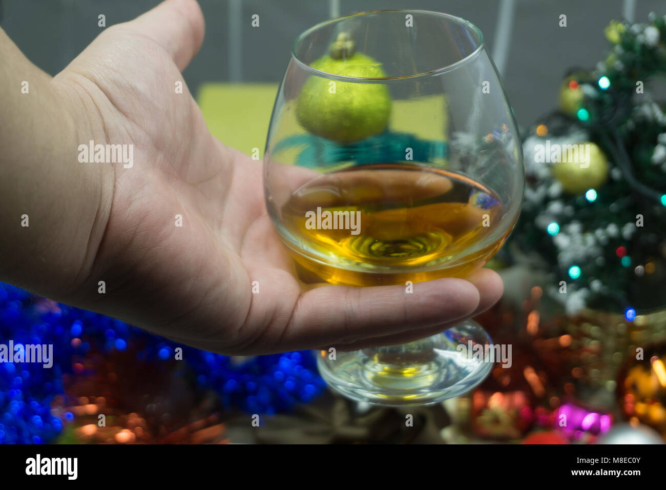 Hand with glass of cognac over black background. Focus on hand with ...