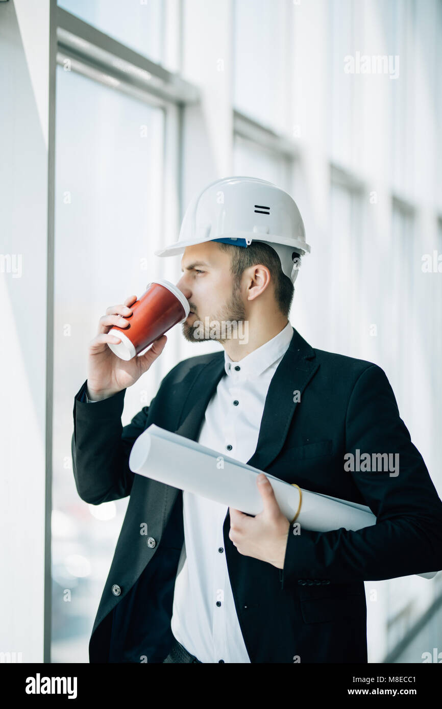 engineer drink coffee with blueprint in hands before inspection of ...
