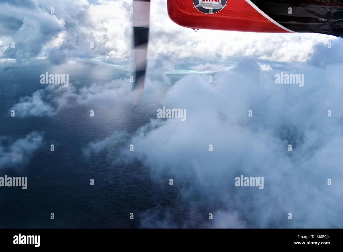 Aerial view from a seaplane flying through the clouds over Maldive ...